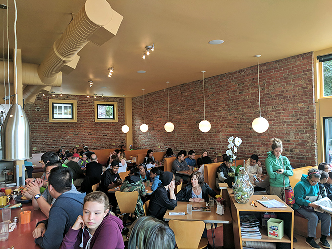 Weekend warriors and breakfast enthusiasts gather under brick walls and globe lights, united in their pursuit of the perfect morning meal.