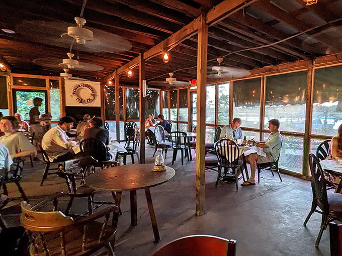 The screened porch dining area &ndash; where the coastal breeze mingles with the aroma of fresh seafood and conversations flow as easily as the nearby tides.