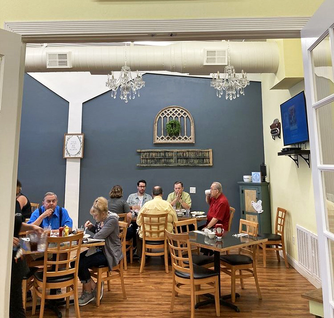 Diners enjoying their meals under elegant chandeliers &ndash; because Dena's Place understands that comfort food deserves a touch of unexpected glamour. Fancy meets familiar in perfect harmony.