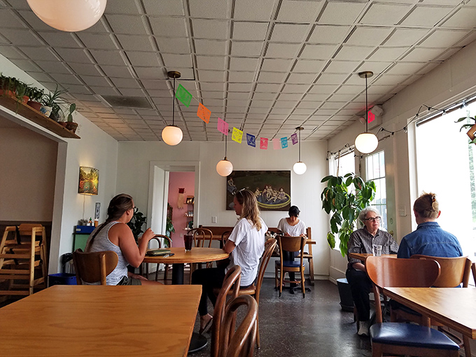 The true measure of a great caf&eacute;: people lost in conversation, savoring both the food and the moment, under cheerful papel picado banners.