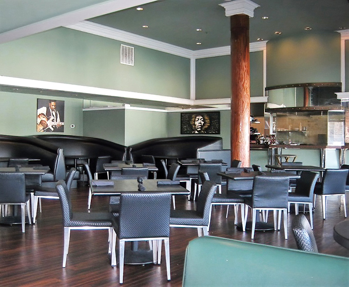 Mint walls and wooden beams create a sophisticated yet relaxed atmosphere where music legends watch over your meal from stylish black and white portraits.