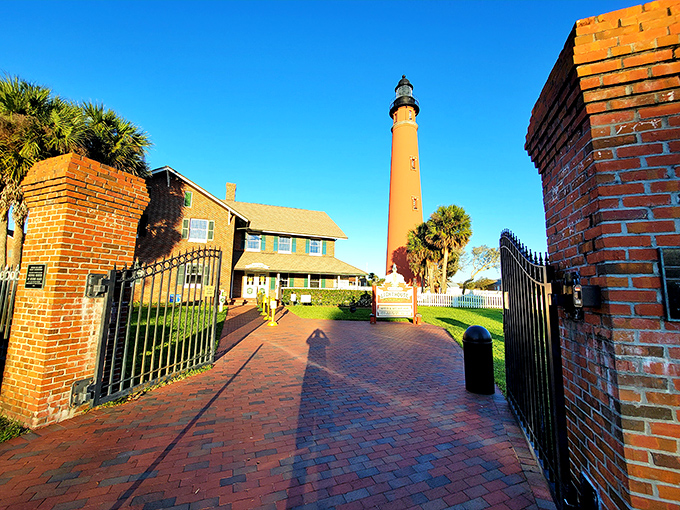 The brick entrance path practically rolls out the red carpet to history, inviting visitors through wrought iron gates that have welcomed generations of curious explorers.