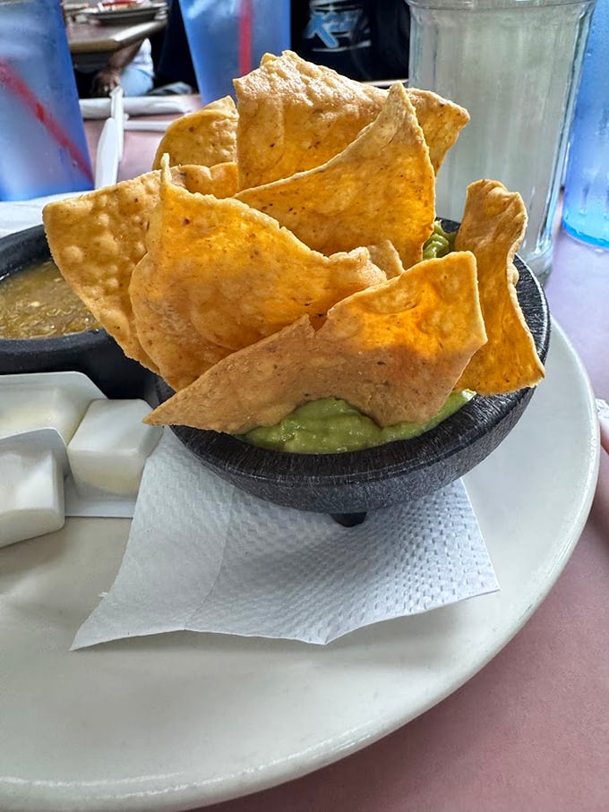 Guacamole nestled in its stone molcajete with chips standing at attention, ready for their inevitable delicious demise.