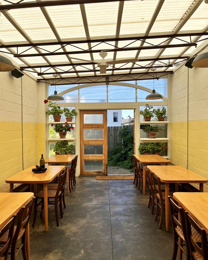 The sunlit greenhouse dining section feels like eating in a botanical garden, where plants are both your dining companions and, ironically, your dinner.