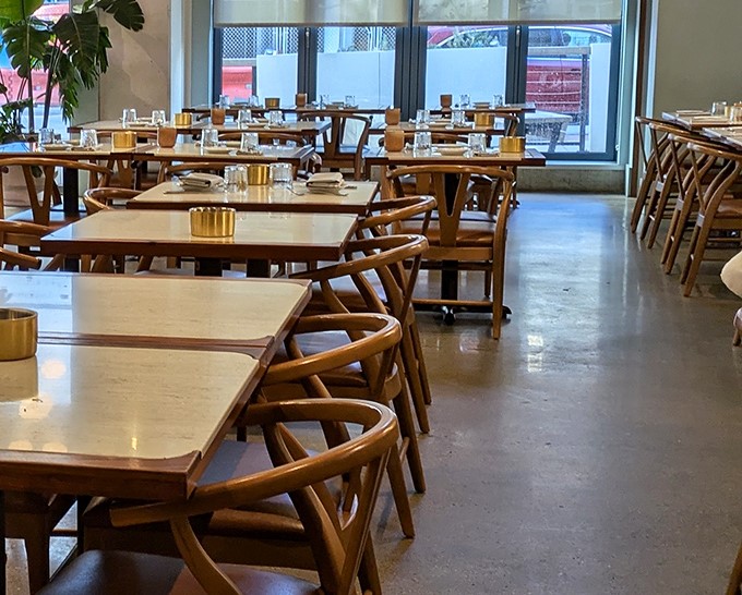 Tables await their diners like blank canvases, each marble-topped surface ready for the edible masterpieces about to grace them.