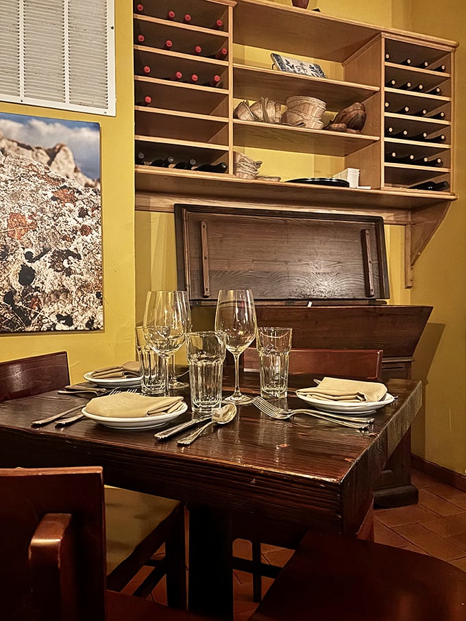 Wine bottles standing at attention like soldiers guarding flavor. This cozy nook invites intimate conversations and lingering over that last glass of Montepulciano.