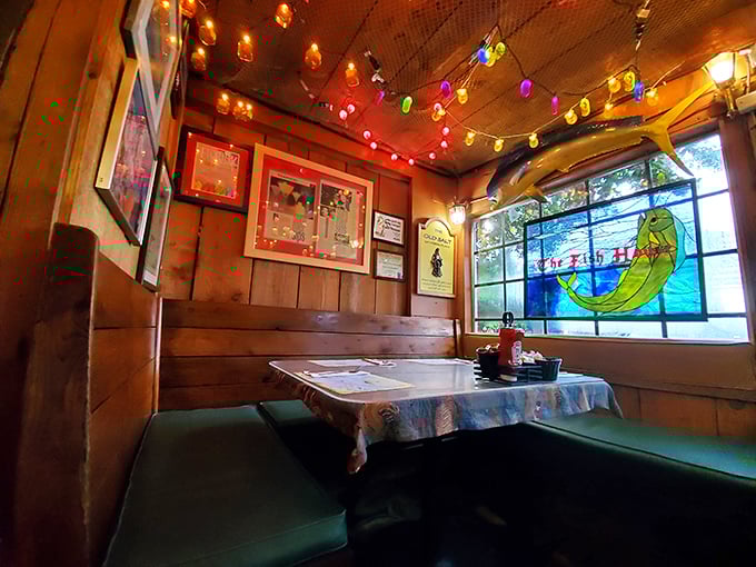 Cozy booth seating beneath a stained glass mermaid window&mdash;this corner spot feels like being inside a ship captain's favorite hideaway.