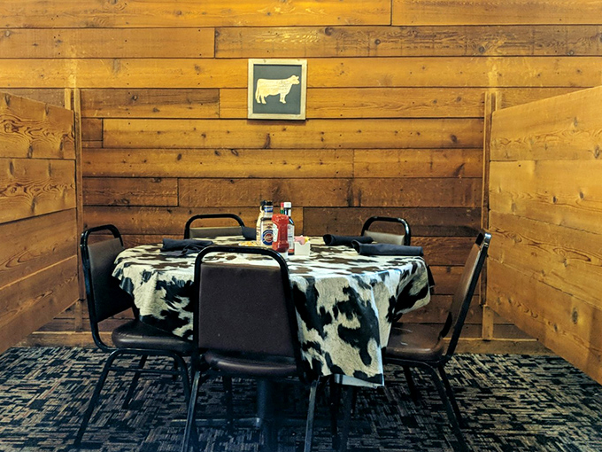 Rustic wood paneling and cow-print tablecloths create a dining nook that feels like a secret clubhouse for serious steak enthusiasts.