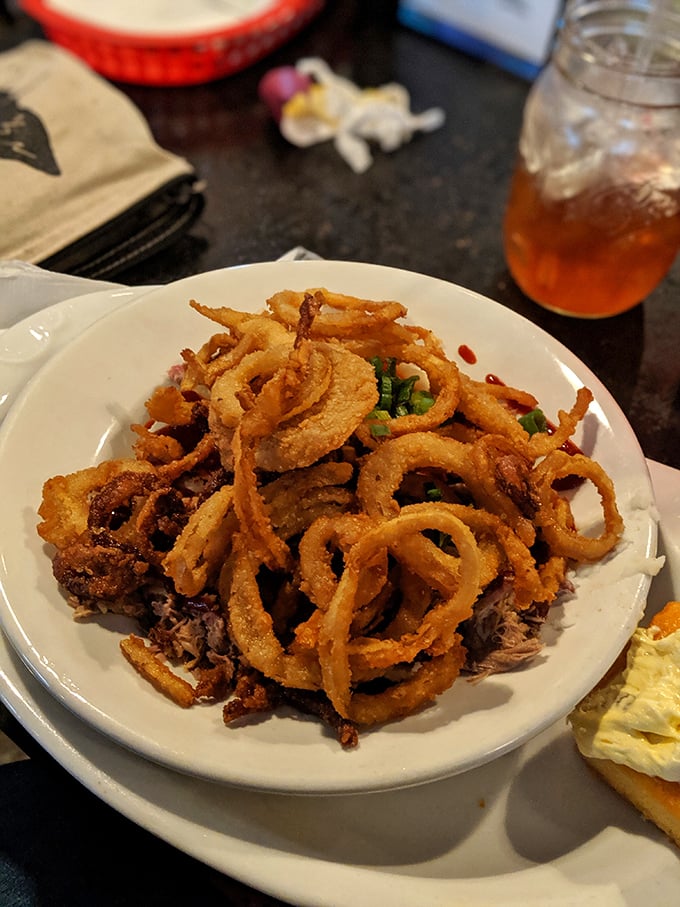 These crispy onion rings aren't just a side dish &ndash; they're golden halos crowning a kingdom of pulled pork below.