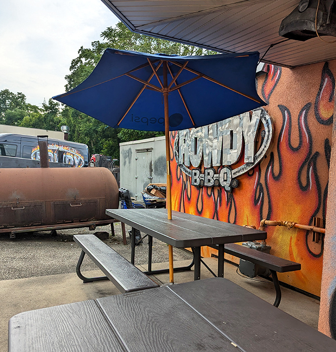 A flame-painted wall, blue umbrella, and picnic tables &ndash; the outdoor dining area is BBQ's version of al fresco elegance.
