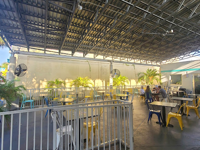 The covered patio space feels like dining in a secret garden, where yellow chairs pop against lush greenery and conversations flow as freely as the iced tea.