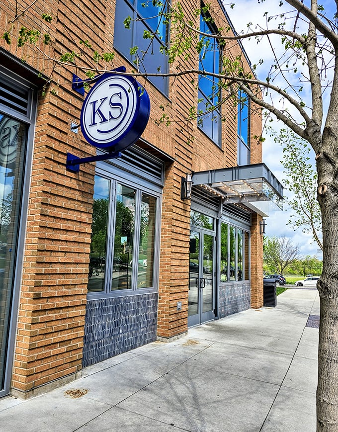 The KS logo beckons from warm brick walls. Like a secret handshake among food lovers, this sidewalk view promises delicious conspiracies within.