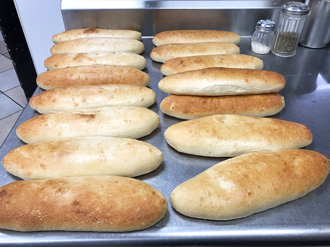 Fresh sub rolls lined up like soldiers ready for duty. There's something deeply satisfying about bread that's prepared with such military precision.