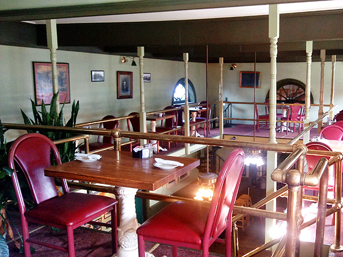 Ruby-red chairs pop against warm wood tones in this dining car seating area. The brass railings aren't just decorative&mdash;they're portals to railroad dining's heyday.