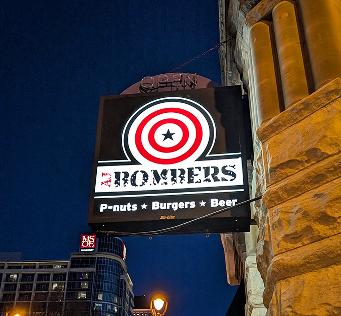 As night falls, the AJ Bombers sign glows like a beacon for the burger-obsessed. "P-nuts &bull; Burgers &bull; Beer" is less a tagline than a promise.