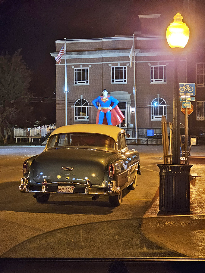 By night, the statue takes on a different character, watching over vintage cars and empty streets like a silent guardian.