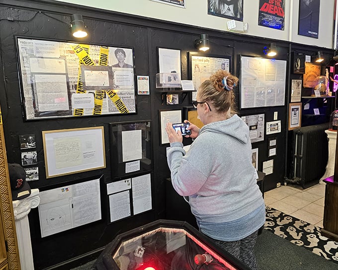 A visitor examines the true crime section, where newspaper clippings and memorabilia document humanity's darkest moments.