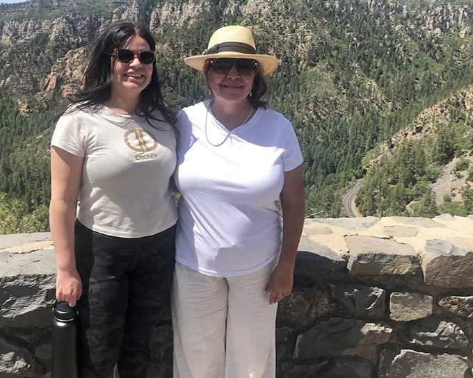 Two visitors share a moment of awe at the canyon's edge, their expressions worth a thousand words – most of them variations of "wow."
