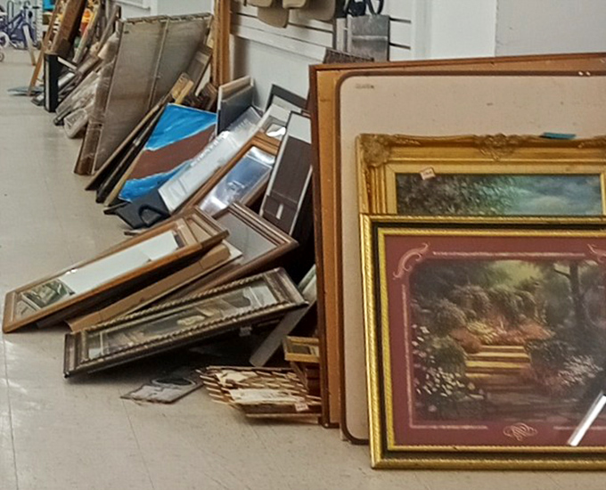 The frame graveyard: where abandoned art and empty frames lean against each other, dreaming of walls they'll someday adorn.