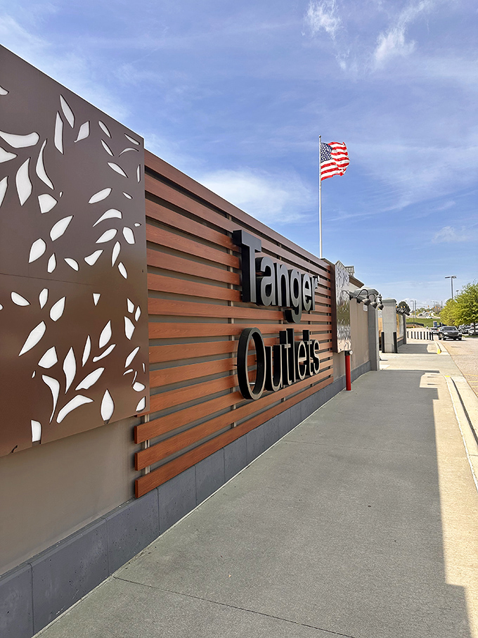 The Tanger Outlets entrance sign stands proud, like a monument to the religion of retail therapy that awaits beyond.
