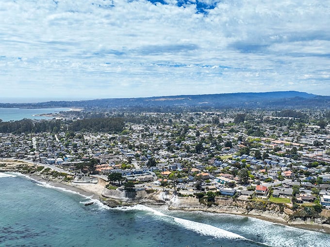 Capitola's rainbow-colored houses reflect in calm bay waters, creating a Mediterranean village vibe in California's oldest seaside resort town.