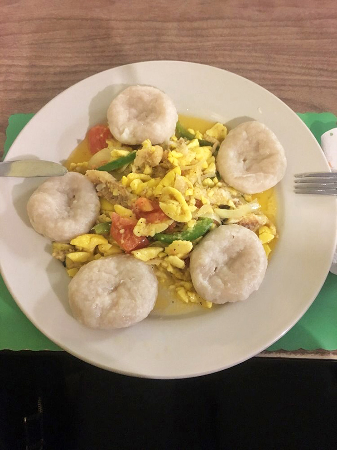 Ackee and saltfish surrounded by dumplings&mdash;Jamaica's national dish looking like sunshine on a plate, ready to brighten your day.