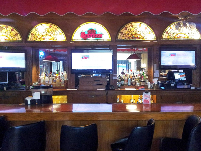 The bar area gleams with stained glass accents above, creating a warm glow that makes every drink feel like a special occasion.