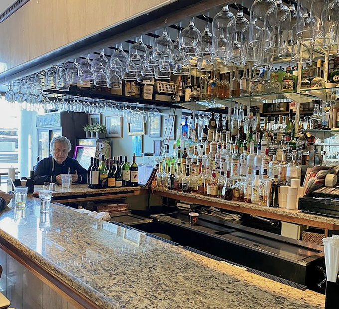 The bar where strangers become friends and regulars are royalty. Notice how the glasses hang like crystal stalactites, ready for action.