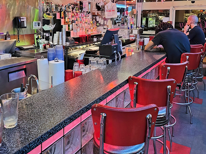 The classic diner counter where solo diners become temporary family and coffee flows like conversation.