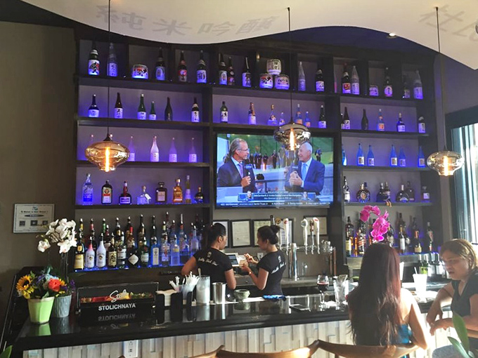 The well-stocked bar glows with blue light, offering liquid courage for first-time shabu shabu adventurers and celebration sips for veterans.
