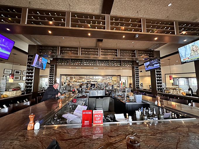 The bar area, where wine bottles stand at attention like soldiers guarding liquid treasures, ready to complement your perfect steak.