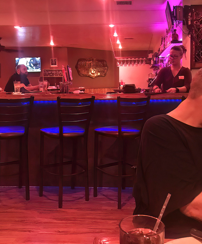 The bar area glows with that perfect mix of ambiance and practicality &ndash; dark enough to feel cozy, bright enough to see your drink. The kind of place where strangers become friends.