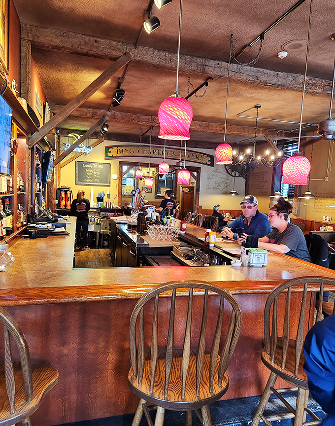 The bar area beckons with its warm wood tones and colorful pendant lights – a place where "I'll just have one" becomes a pleasant fiction.