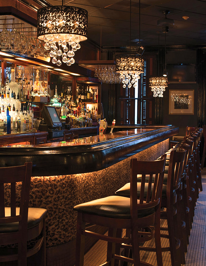 The bar gleams under crystal chandeliers like something from a Gatsby dream. Those bar stools have heard some stories, and they're waiting for yours.
