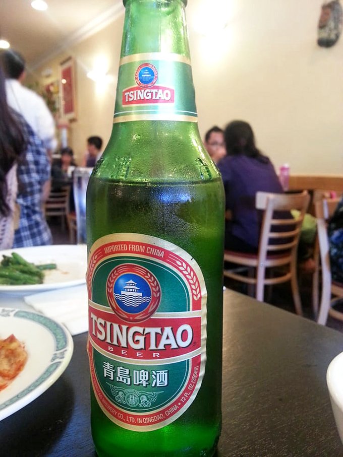 A frosty Tsingtao beer standing at attention, ready to extinguish any spice-induced fires and complement the umami parade.