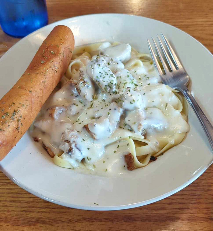Fettuccine Alfredo with a breadstick standing at attention&mdash;comfort food that whispers "take a nap after this" with every creamy bite.