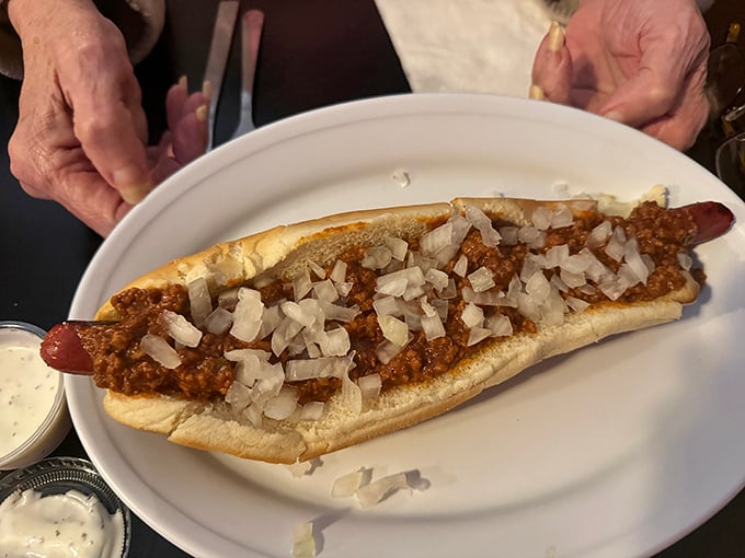 The chili dog in its natural habitat—a canvas of beef, sauce, and diced onions that transforms a simple hot dog into an edible masterpiece.