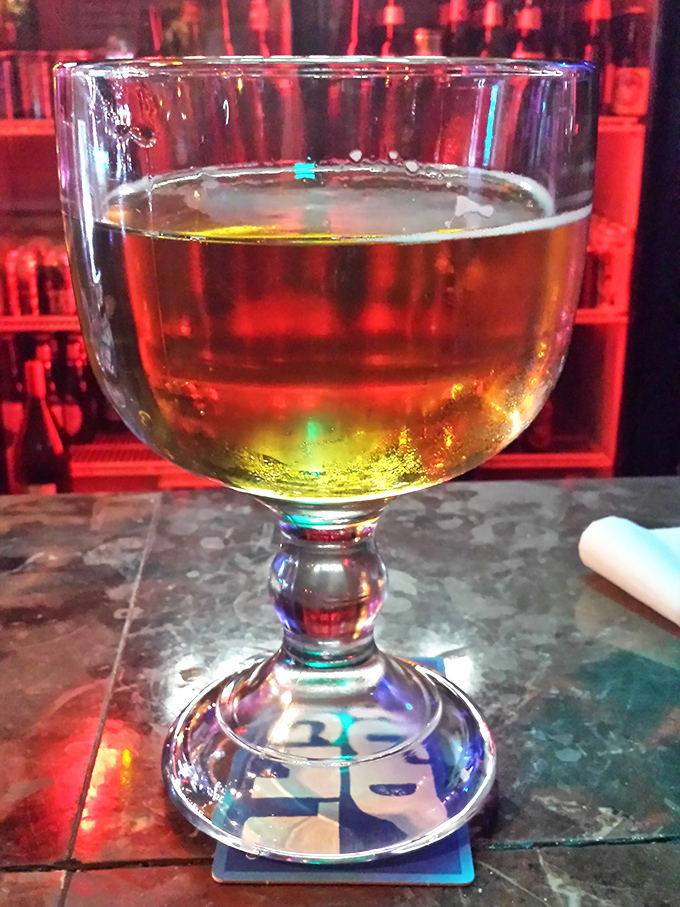 Amber liquid catching the bar lights just right—this isn't just a drink, it's liquid sunshine in a goblet.