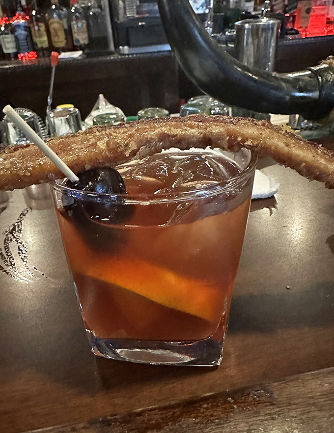 That's not just a Manhattan &ndash; it's a liquid amber time machine garnished with what appears to be bacon candy, because regular garnishes are for amateurs.