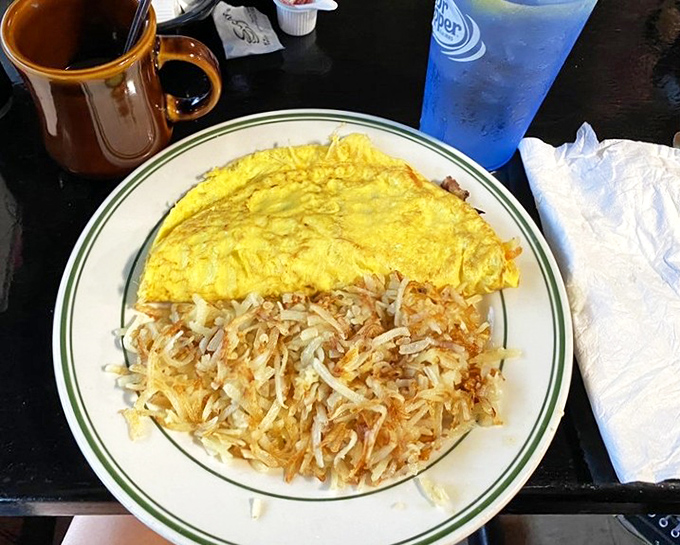 Morning ambition in omelet form, paired with hash browns so crispy they practically shatter at the touch of a fork.