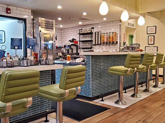 Mid-century modern meets comfort at the counter, where those green chairs practically whisper, "Stay awhile, order another milkshake."