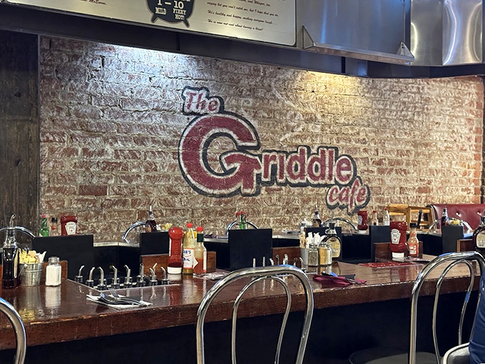 The Griddle's logo watches over diners like a benevolent breakfast deity. That brick wall has witnessed countless sugar-induced epiphanies.