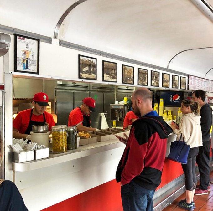 The ordering counter—where dreams become reality. Staff in bright red shirts stand ready to transform your hunger into happiness with remarkable efficiency.