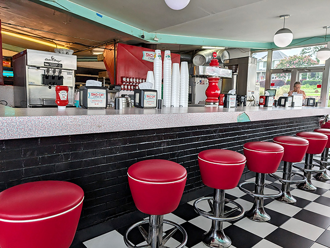 The counter view&mdash;where burger anticipation meets soda fountain artistry under the glow of vintage lighting. 