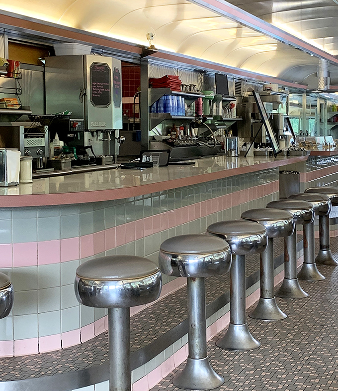 The counter's pink and mint tile work is pure mid-century magic, with those chrome stools practically begging you to spin around just once when nobody's looking.