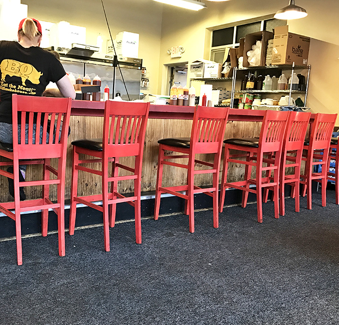 Counter seating: where barbecue pilgrims can watch their smoky dreams become reality. Those red chairs aren't just seating—they're front-row tickets to the show.