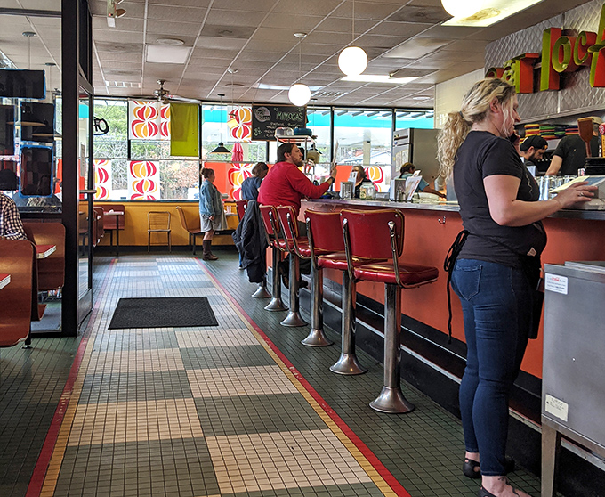 Red stools line the counter where strangers become friends over coffee refills and shared recommendations.