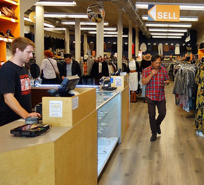 The buy-sell-trade model in action as customers and staff engage in the delicate dance of fashion commerce under the watchful eye of security mirrors.