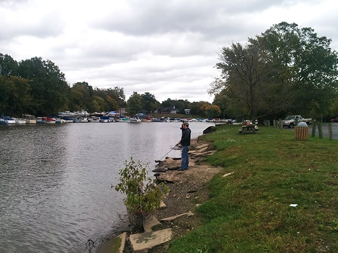 A lone angler tests his luck along the Vermilion River, participating in the town's oldest recreational tradition with quiet determination.