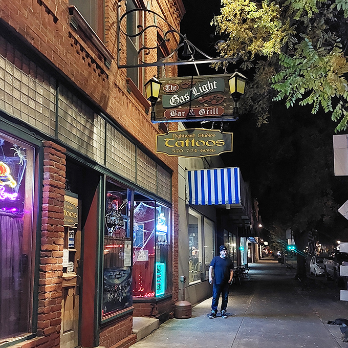 Night transforms The Gas Light Bar & Grill into a glowing haven of conviviality, where the illuminated sign promises good times in this charming brick building.